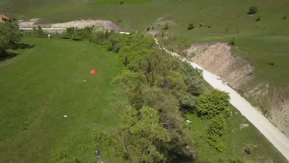 Aerial view of wide open green meadow with a small orange tent. Drone ...