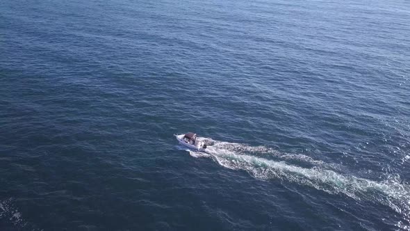 Single small white motoric fishing boat crossing the ocean, Aerial top ...