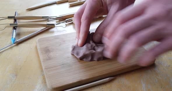 Close up on the hands of an artist sculpting and shaping brown modeling ...