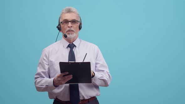 Adult Male Cameraman in a Headset Talks and Holds a Paper Tablet in the ...