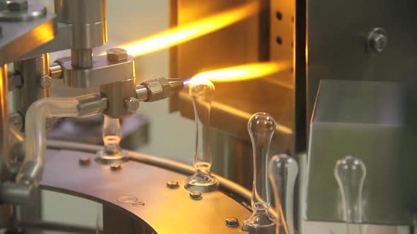 Glass medical vials being molted open by fire in machine., Stock Footage