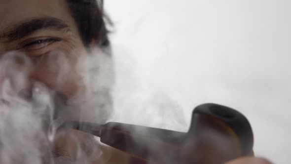 Man is Smoking Pipe and Exhaling a Lot of Fume From Nostrils Frowning ...