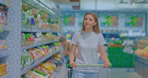 Cute Girl is Walking Around the Store with a Grocery Cart Shopping at ...