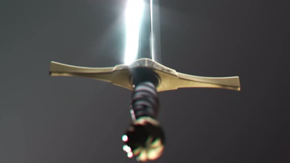 Old medieval sword shining in a spotlight. Light reflects in a sharp ...