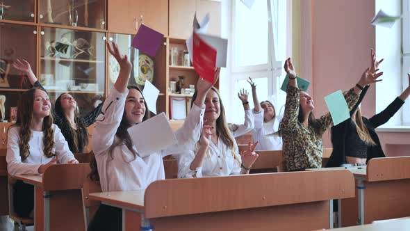 Pupils Sitting at Their Desks in the Classroom Throw Notebooks Up ...