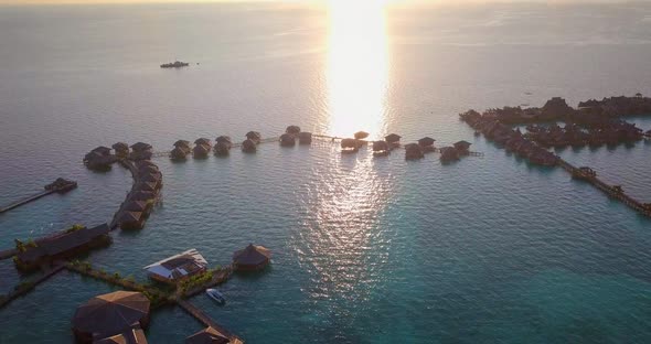 Aerial flight towards stunning sunset over ocean and huts in Mabul ...