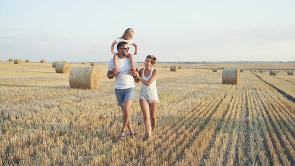 Joyful Family Walk in Field, Girl on Father's Shoulders Shows Thumb ...