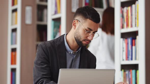 Man Doing Research in Library Using Laptop and Books, Stock Footage
