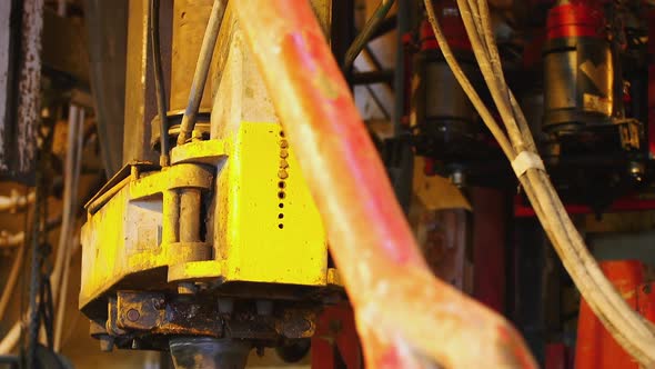 A close-up of the shaft of a drilling rig descending into the ground ...