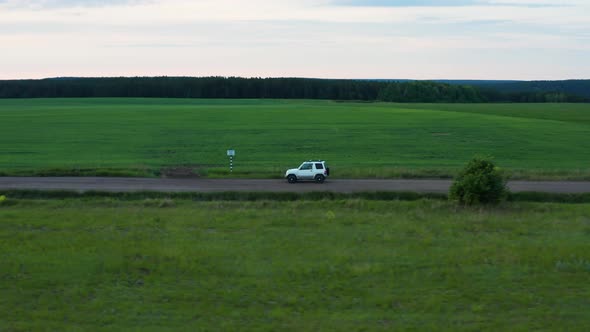 Aerial View of a Car Driving in Nature on a Field at Sunset, Stock Footage