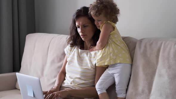 Mother Multitasking Using Laptop Computer at Home with Her Baby ...