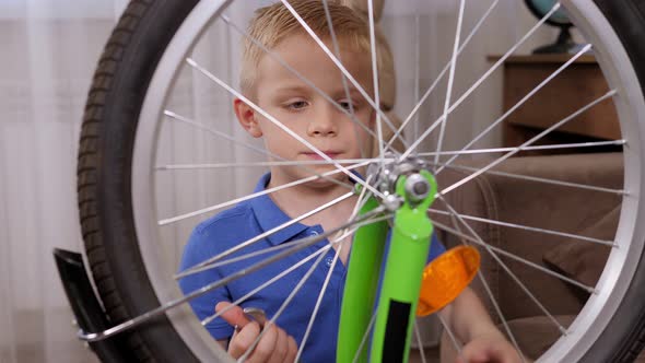 Closeup of a Little Boy Spinning a Wheel on an Overturned Bicycle at ...