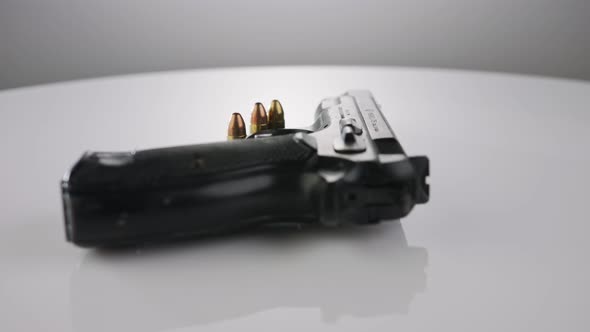 Gun Control. Studio shot of a 9mm gun rotating on a reflective surface ...
