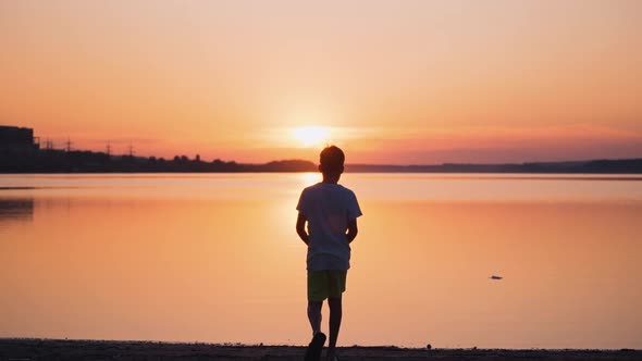 Boy walking into water. Back view of boy silhouette going into water ...