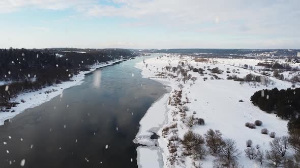 Vast river in winter season during heavy snowstorm, aerial fly forward ...