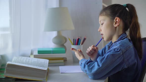 Little School Girl Chewing Pen and Counting on Fingers while Doing her ...
