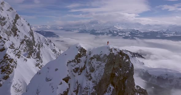 Aerial drone view of a mountain climber skier on the peak summit top of ...