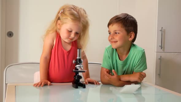 Cute Little Girl and Boy are Sharing a Microscope with Each Other in ...