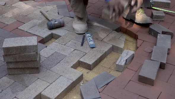Detail of artisan fitting a freshly cut brick into the two-tone paver ...