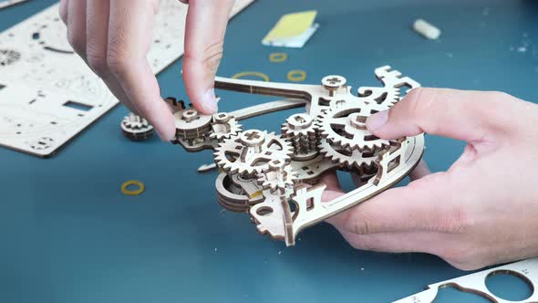 Mechanical wooden toy. Man holding small wooden puzzle details in hands ...