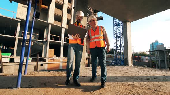 People Walk on a Construction Site with a Laptop. Construction Workers ...