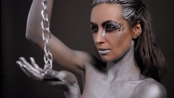Woman with Silver Paint on Her Skin Face and Hair Poses in a Studio ...