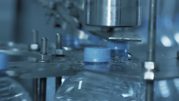 Close-up: Automatic Machine Tighting the Plastic Cap on Plastic Bottle ...
