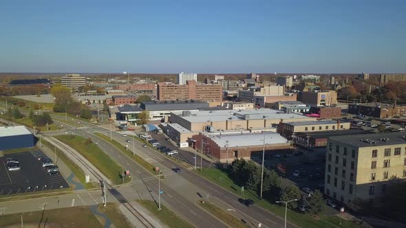 Backward aerial of street traffic through Muskegon, MI, urban area ...