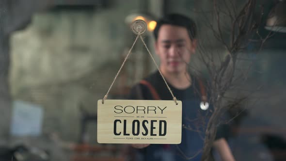 4K Asian man coffee shop owner turning hanging closed sign to open on ...