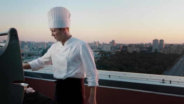 A professional Chef prepares a barbecue on the roof of a skyscraper. An ...