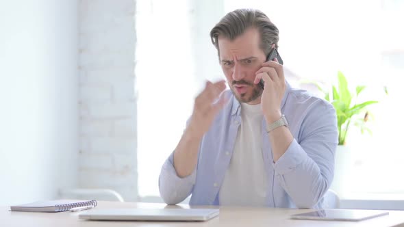 Upset Young Man Talking Angrily on Smartphone in Office, Stock Footage