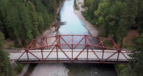 Aerial footage of a red truss bridge spanning a small river., Stock Footage