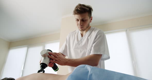 Doctor Treating the Patients Back Muscles with Massaging Percussion ...