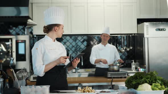 Restaurant kitchen: portrait of male and female cooks. Woman CHEF ...