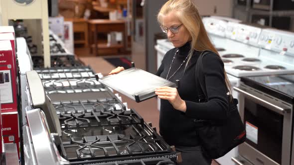 Pretty mature blonde woman looking at the griddle as part of a gas ...