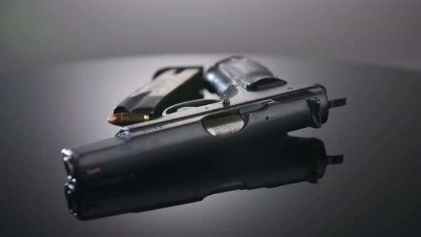Gun Control. Studio shot of a 9mm gun rotating on a reflective surface ...