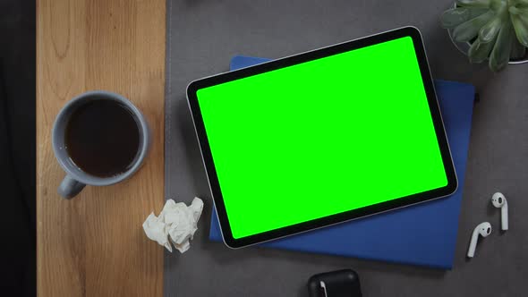 A Tablet with a Green Screen Lies on the Desktop Next to a Cup of Hot ...