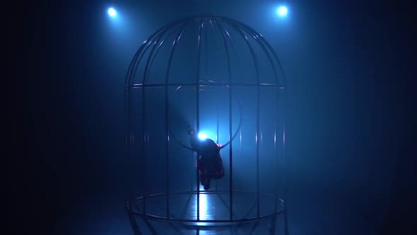 Aerial Acrobatics on a Rotating Hoop in Cage in a Dark Room. Blue Smoke ...