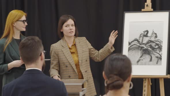 Two Female Auctioneers Presenting Artwork to Buyers, Stock Footage