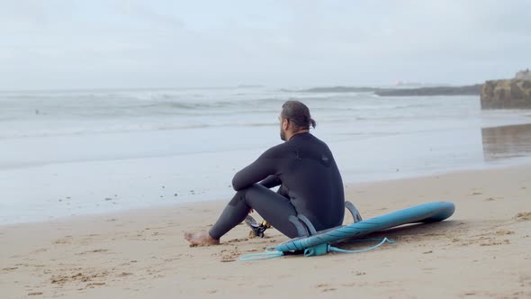 Tired Surfer with Artificial Leg Sitting on Sandy Beach, Stock Footage