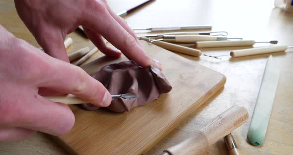 An artist sculpting a project with soft, brown modeling clay and hand ...