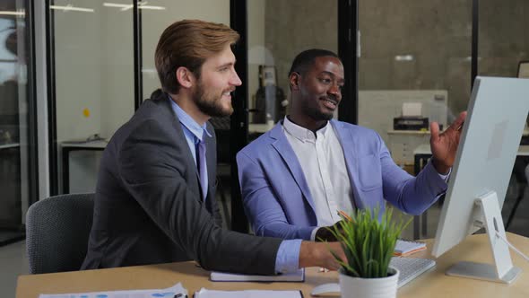 Two business colleagues discussing project at the computer in office ...