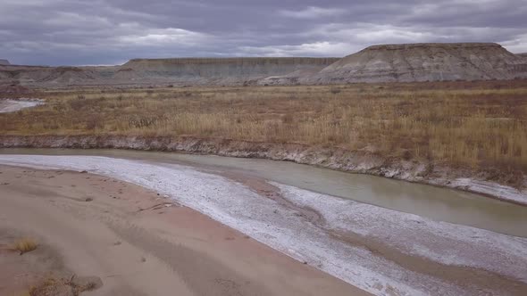 Flying backwards over river flowing through the desert, Stock Footage