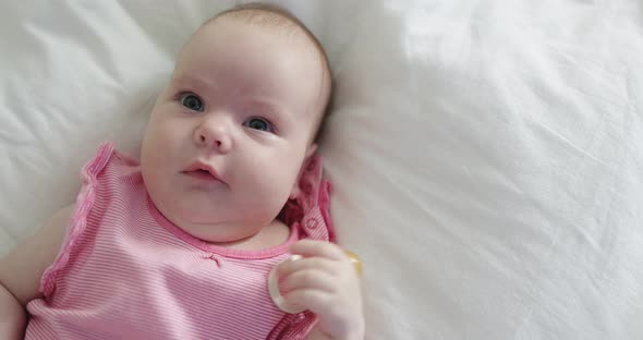 Pretty Chubby Little Baby Girl Wriggling on Her Bed As She Looks Up at ...