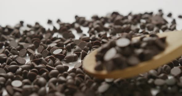 Video of close up of multiple chocolate chip falling on wooden spoon ...
