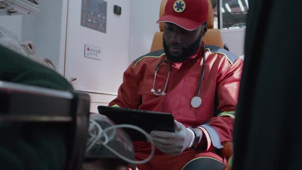 Black Paramedic Checking Vital Signs Monitor and Using Tablet, Stock ...