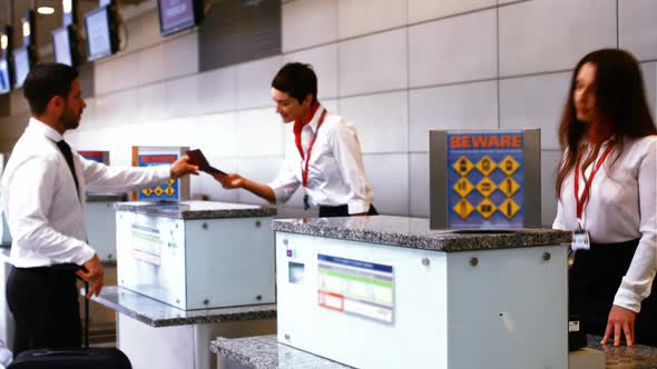 Two female airport staff checking passport and interacting with ...