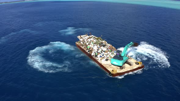 Backhoe on a swimming platform collecting plastic waste from the ocean ...