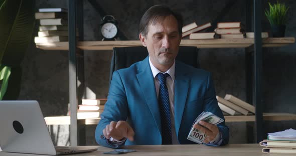 Mature CEO Businessman Sitting at Desk and Counting Money Dollar Bills ...