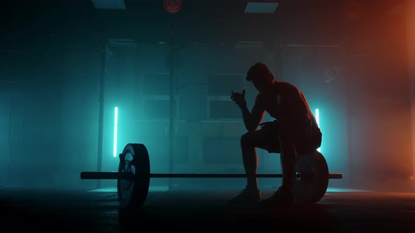 Exhausted and Depressed Sportsman in Dark Gym Sitting Near Barbell and ...